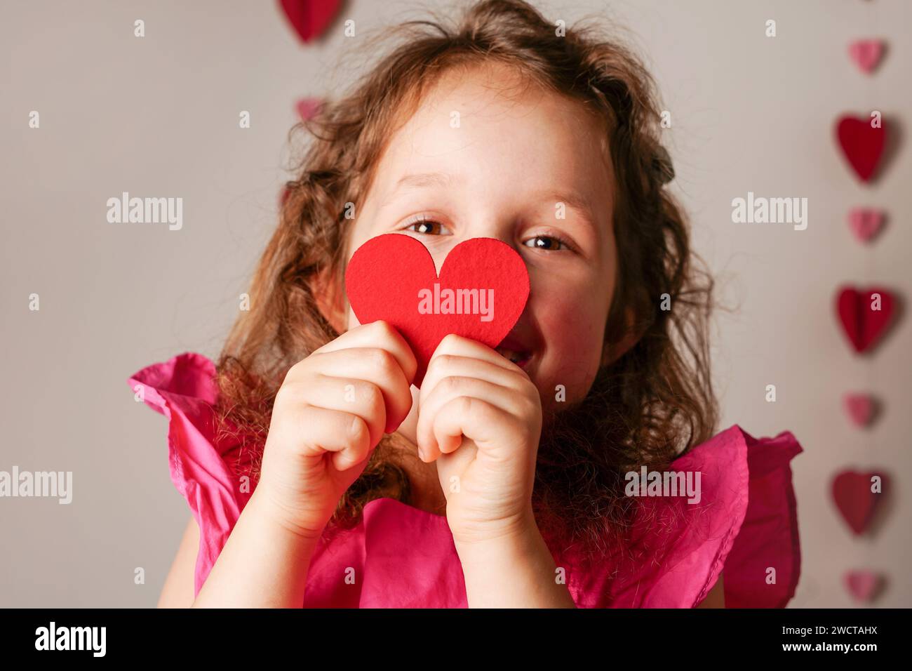 Funky little child girl in pink dress holding red heart and laughs ...