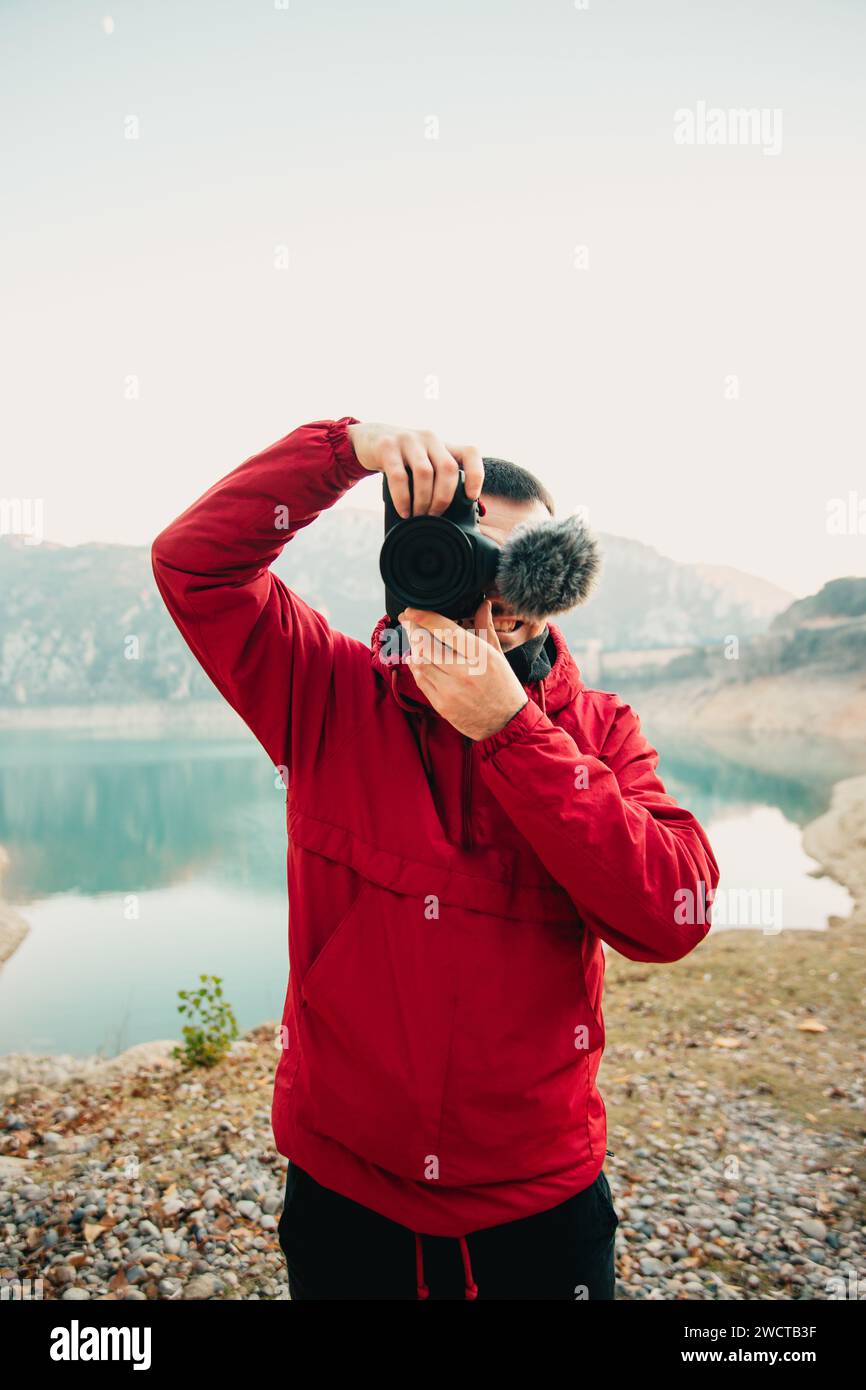 Anonymous photographer in a red jacket capturing the landscape with a ...