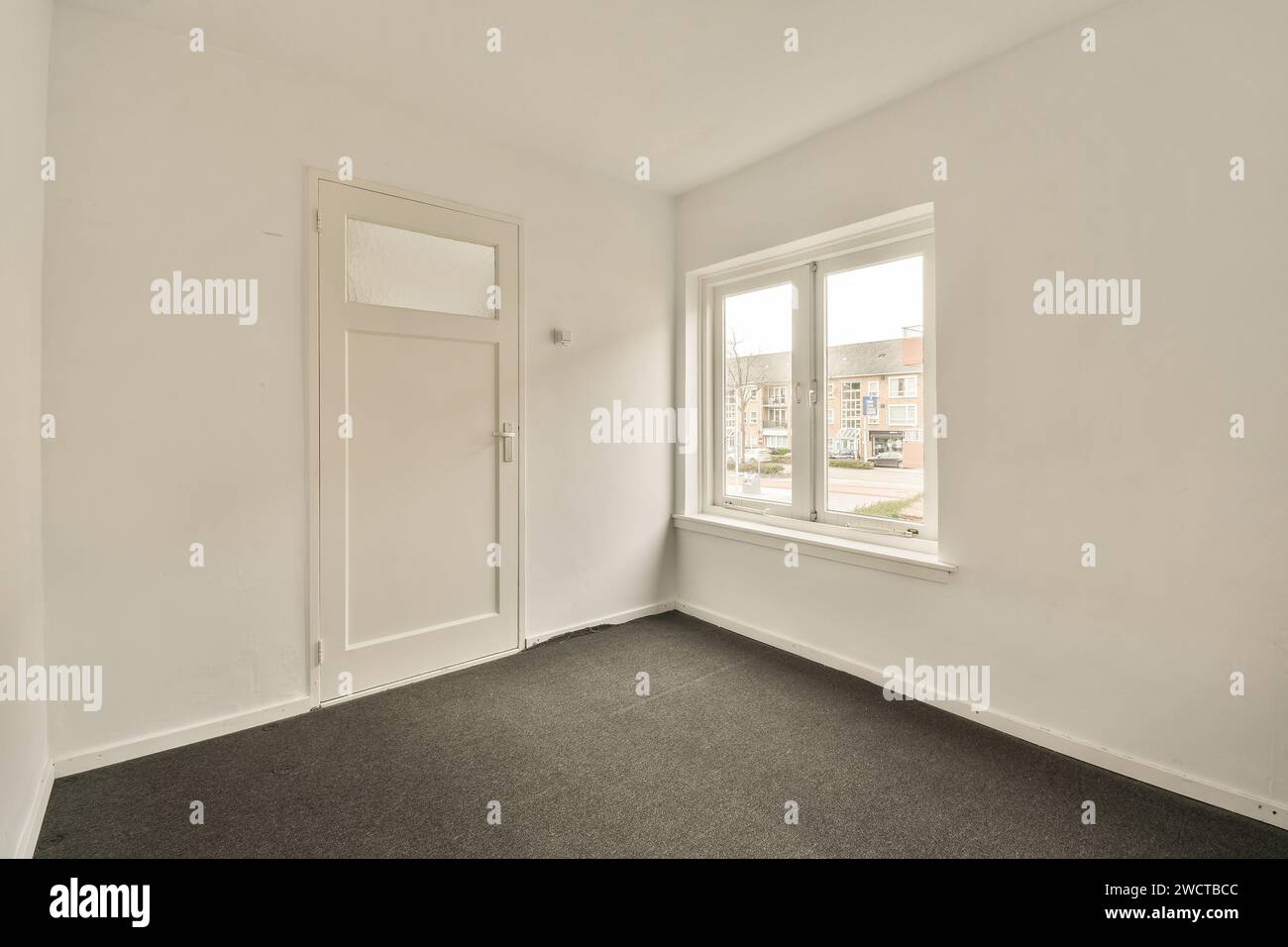 An empty room featuring a large window, freshly painted walls, and a ...