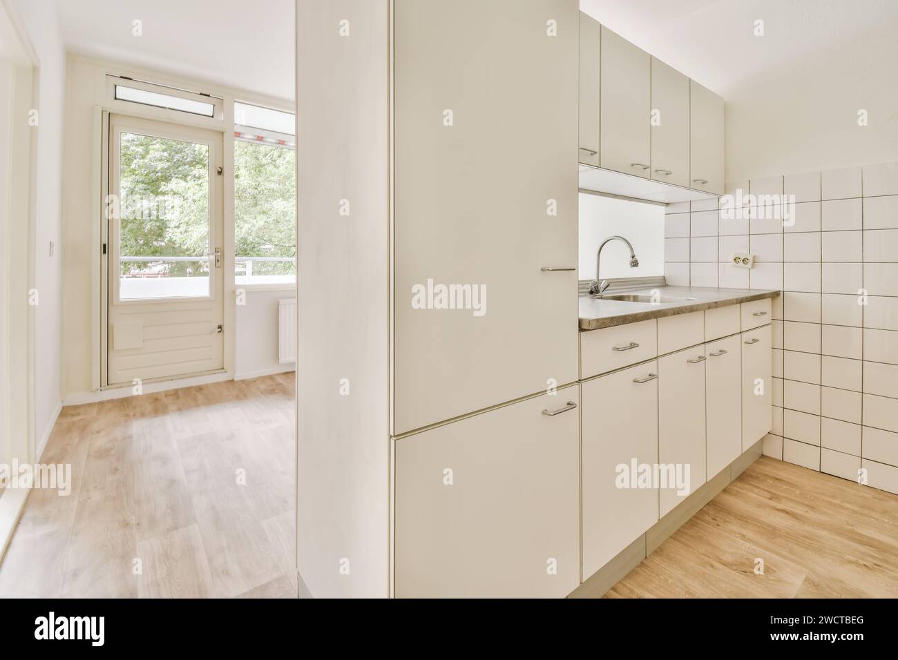A clean, contemporary kitchen space featuring white cabinets, tiled ...