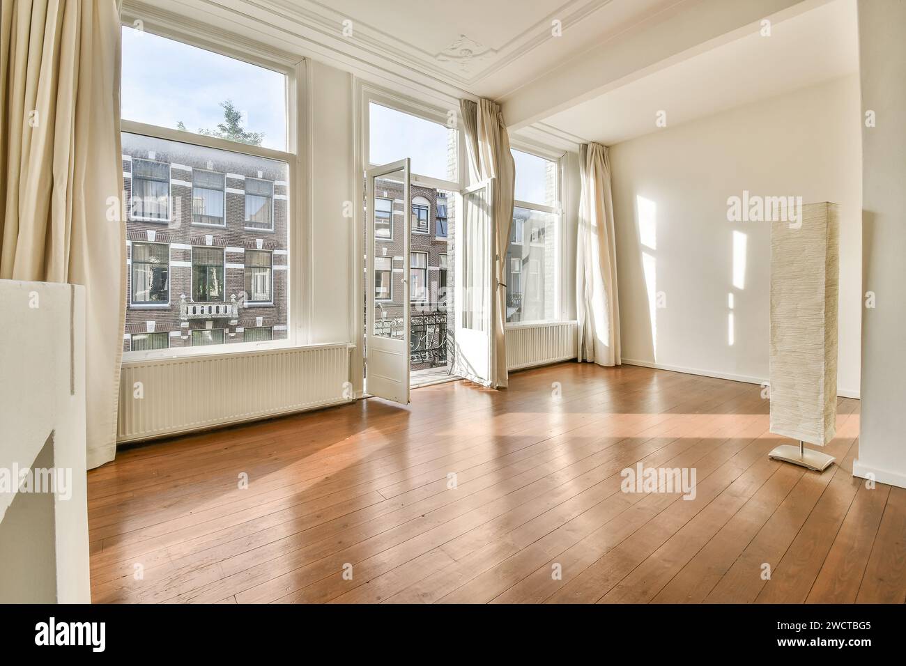 A bright and airy living room showcasing large windows, wooden flooring ...