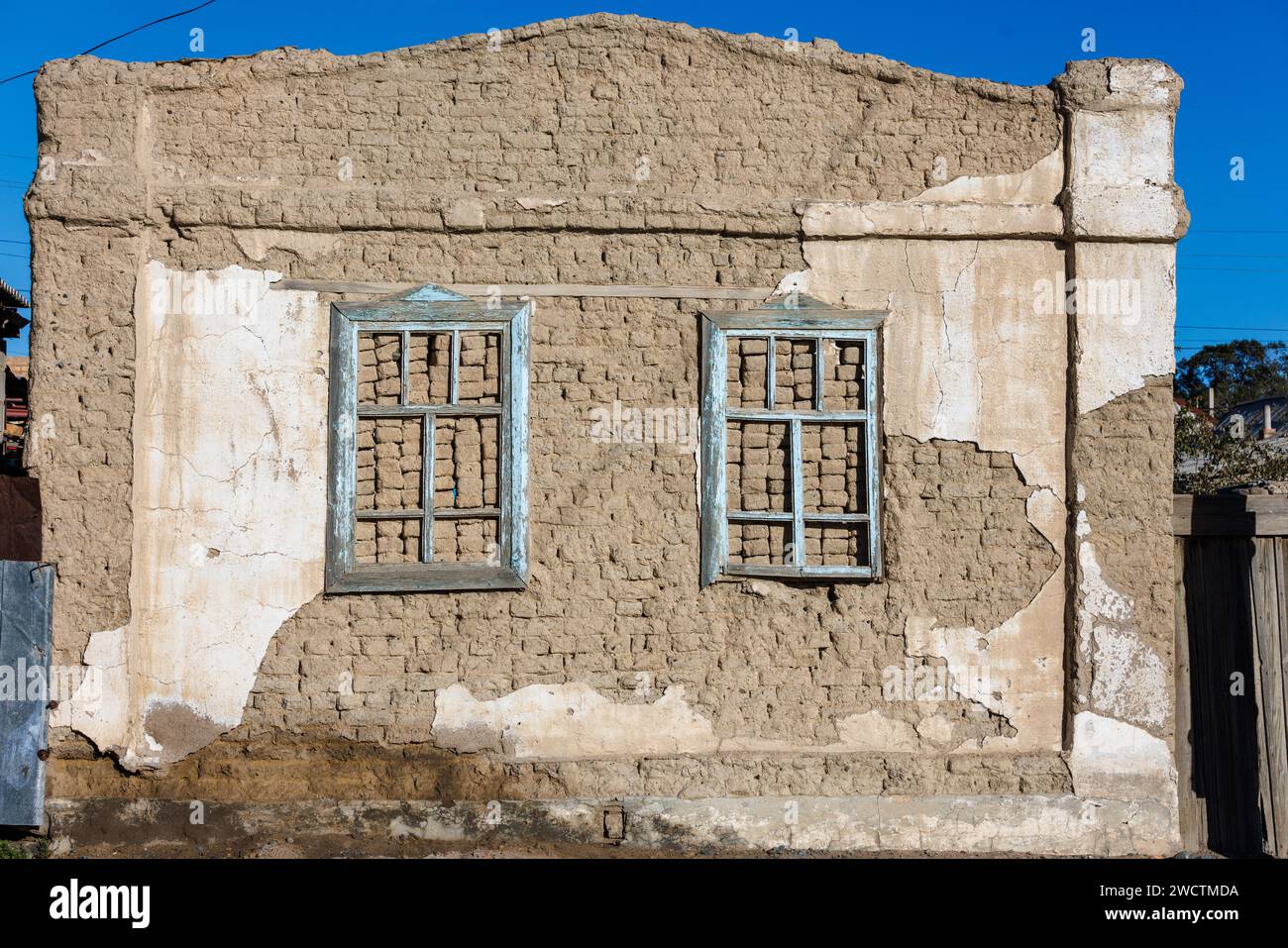 old house adobe air brick wall with two embedded wooden window frames ...