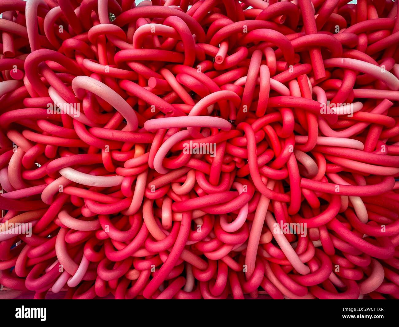 Close-up of a vibrant tangle of red rubber tubes creating an abstract ...