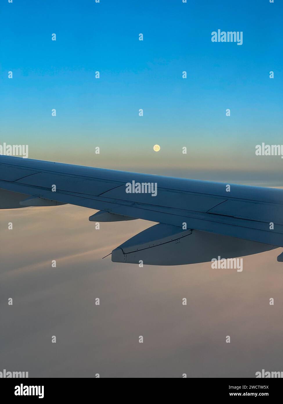 Serene scene from an airplane window with wing and full moon during a ...