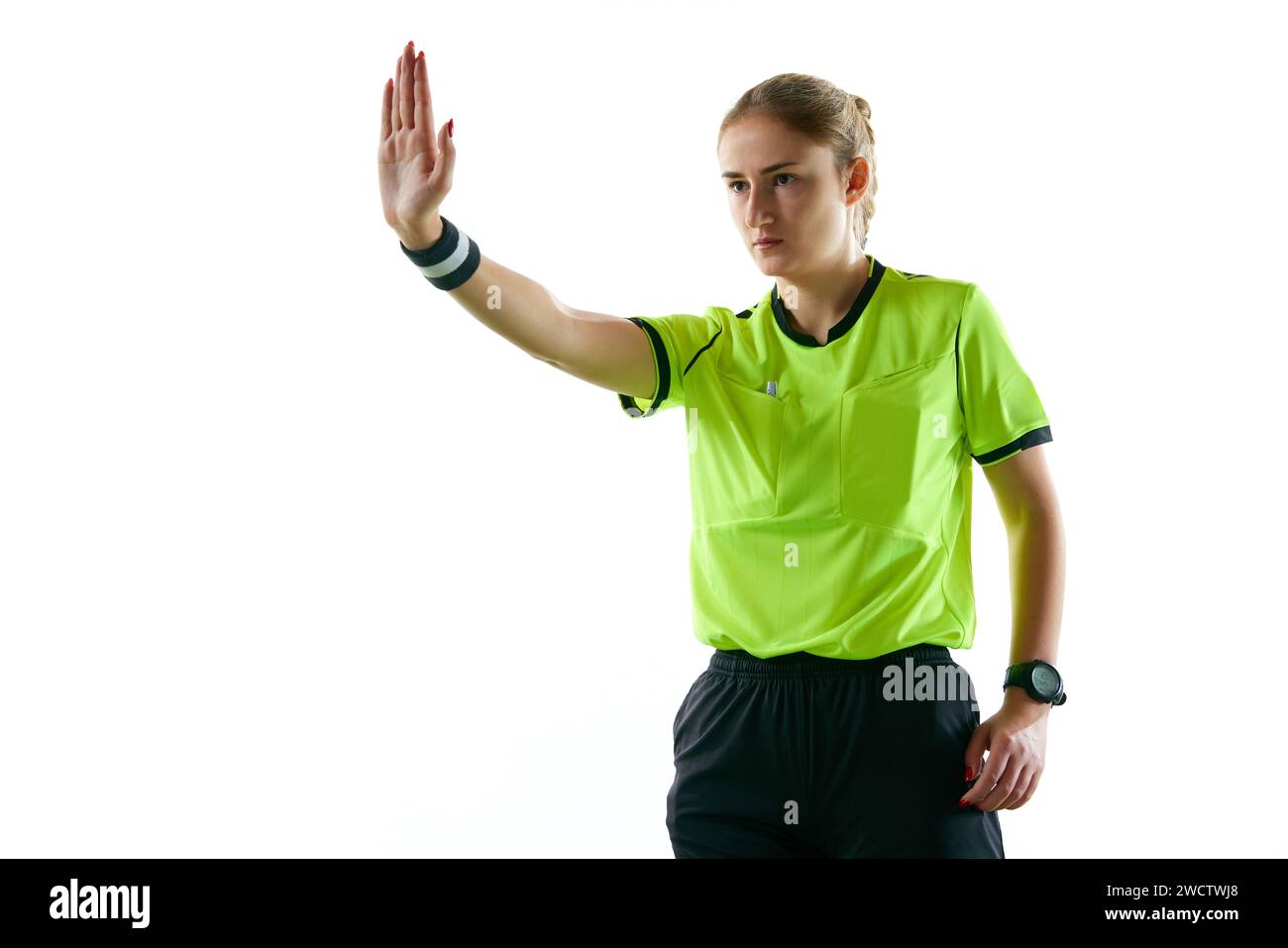 Young serious woman, soccer referee gesturing, raising hand forward ...