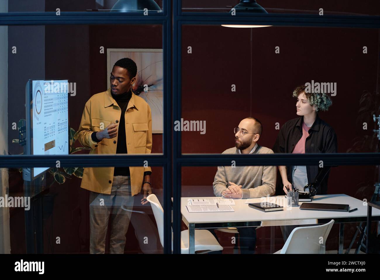 Black office worker showing presentation with infographics to his ...