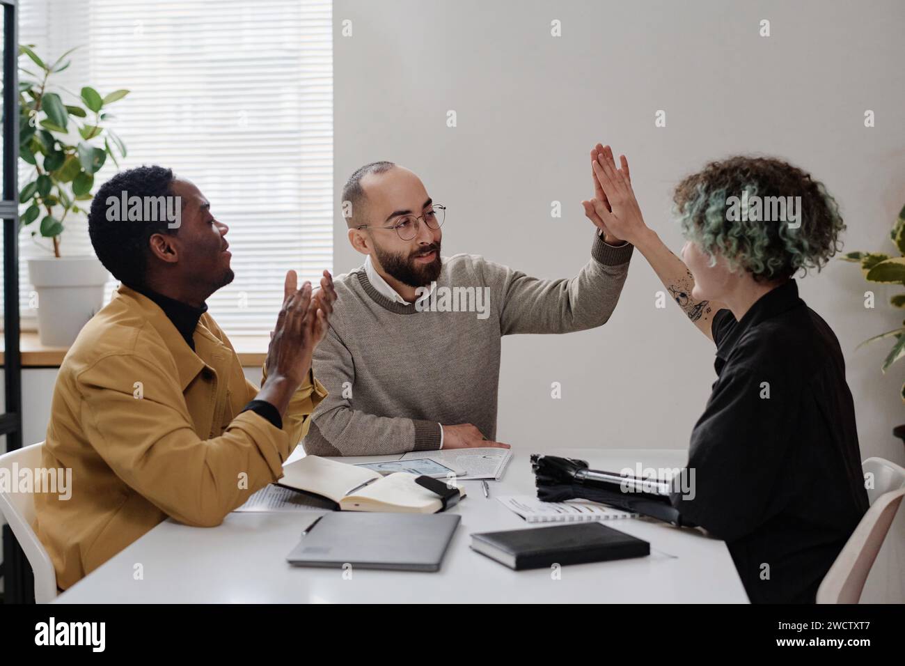 Male and female office workers giving each other high five, their black ...
