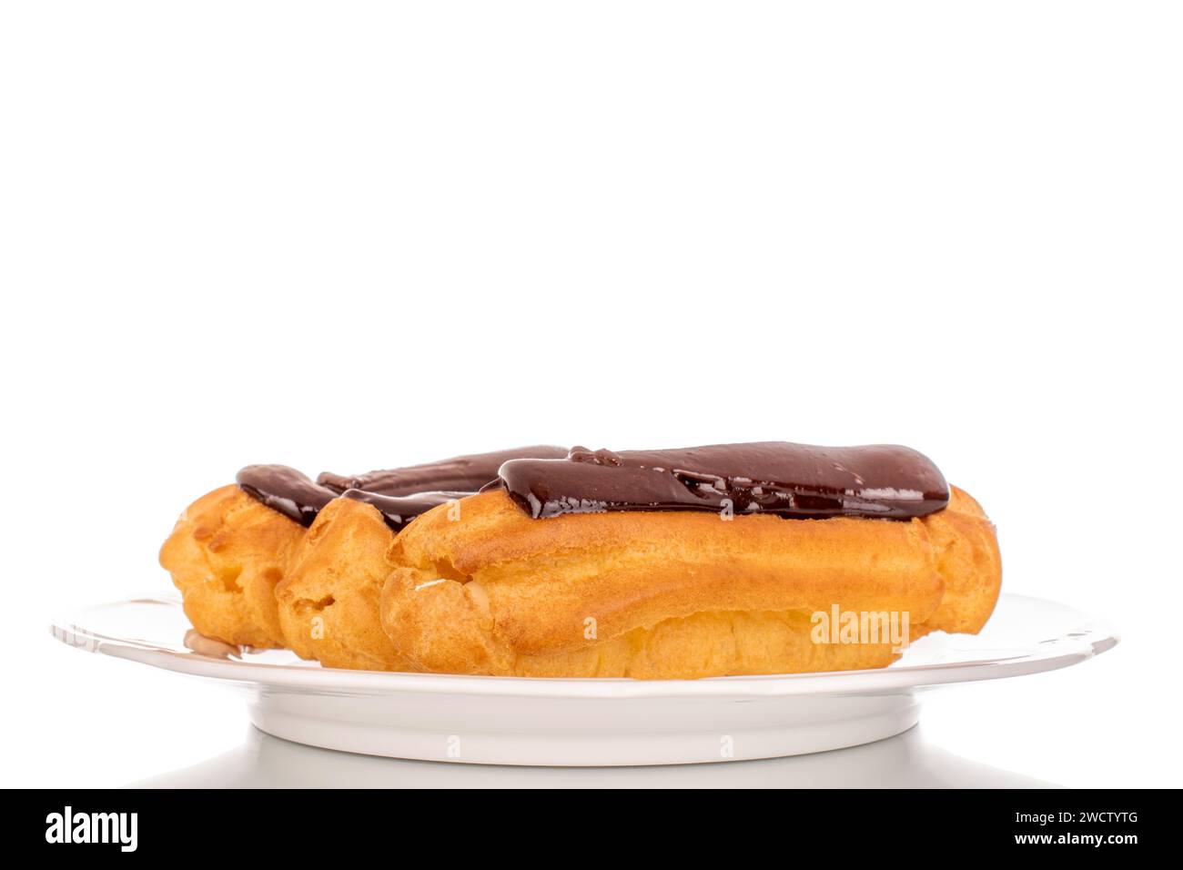 Three sweet chocolate eclairs on a white ceramic dish, close-up ...