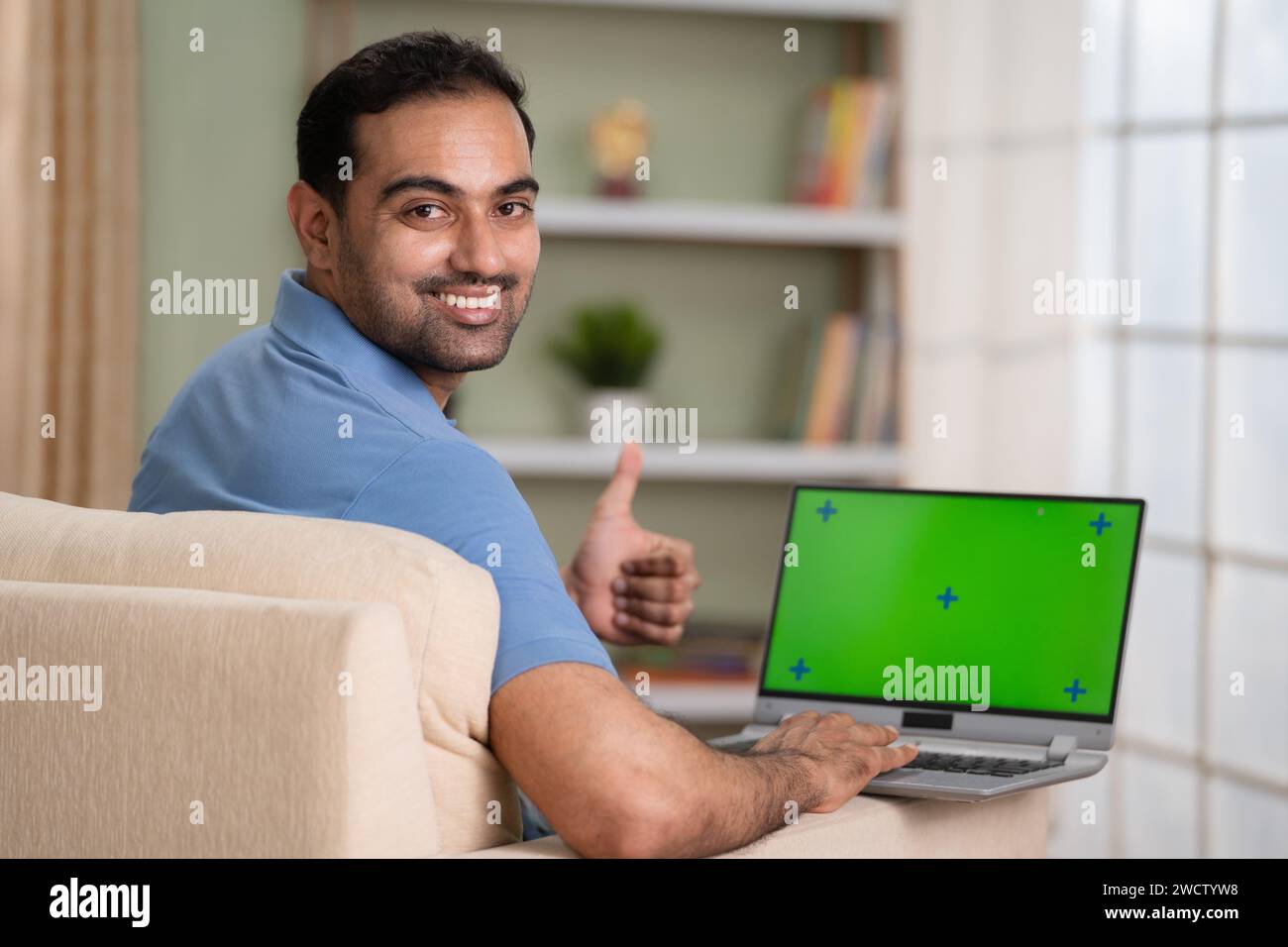 Happy indian man using green screen laptop by showing thumbs up while ...