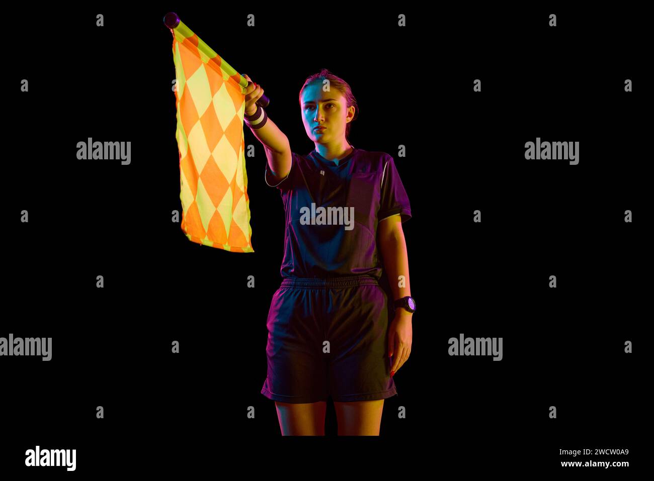 Young serious woman, assistant referee raising flag up meaning offside ...