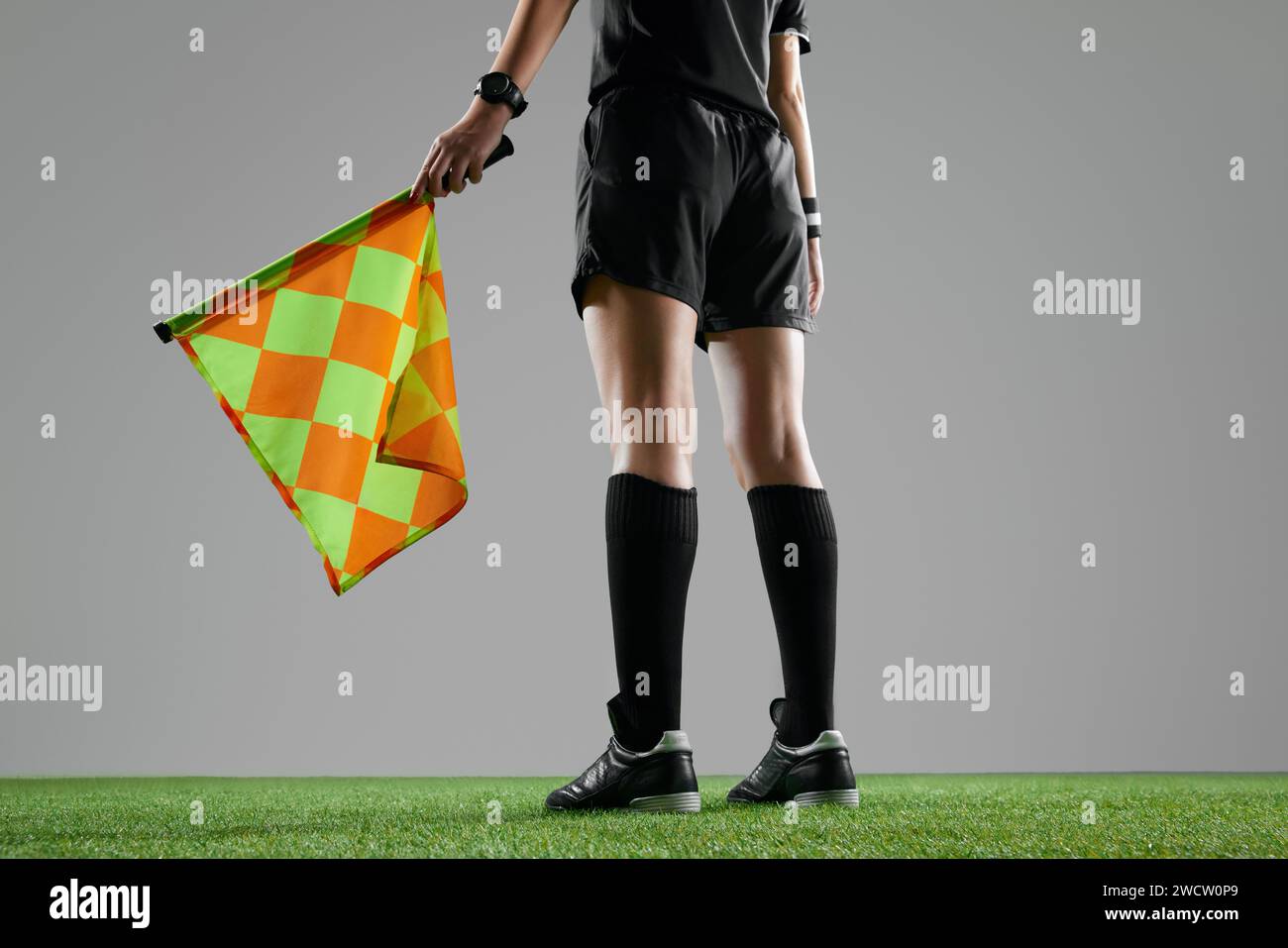 Legs of female referee in sportswear standing with flag, signaling for ...