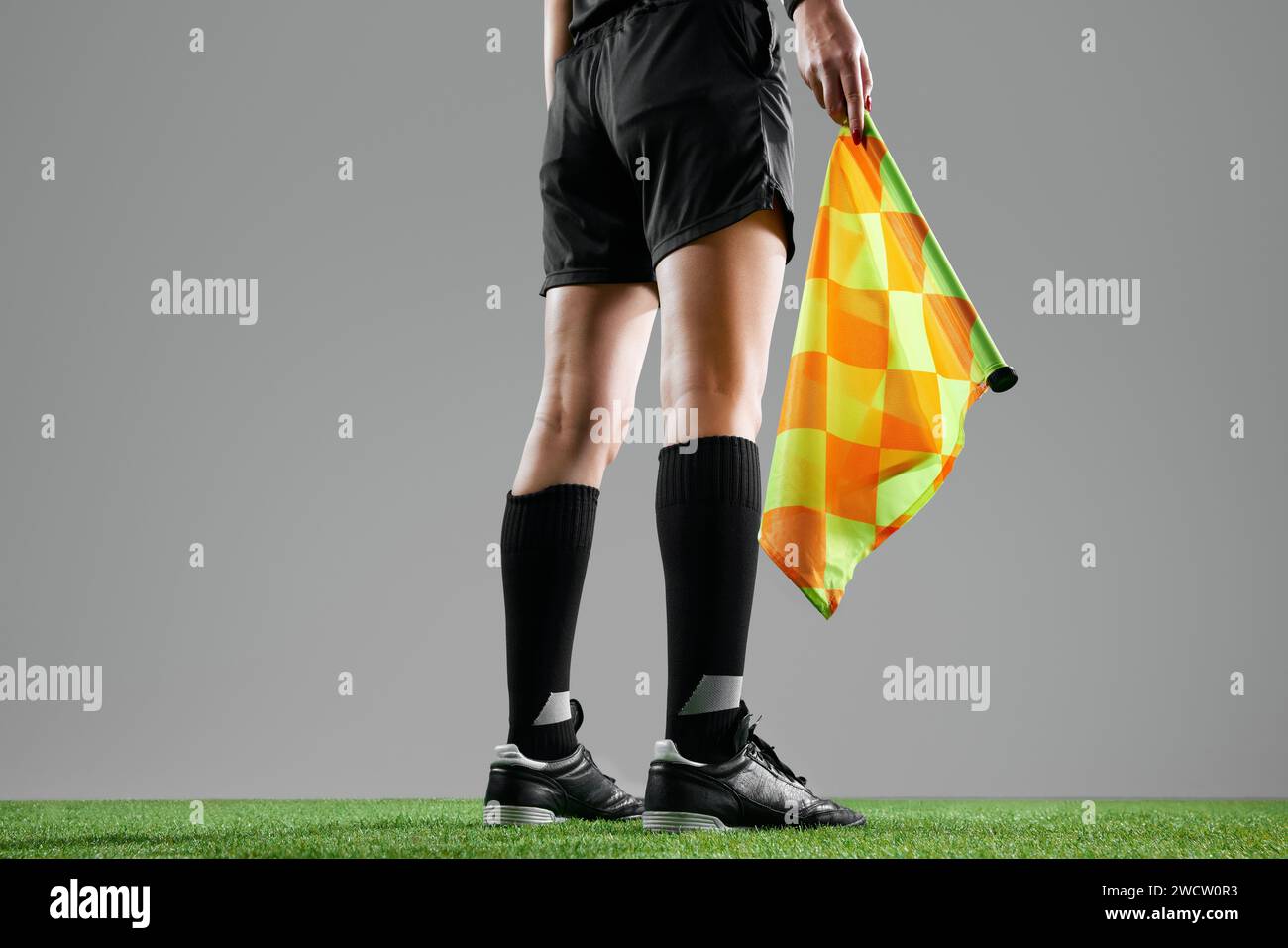 Legs of female referee in sportswear standing with flag, signaling for ...