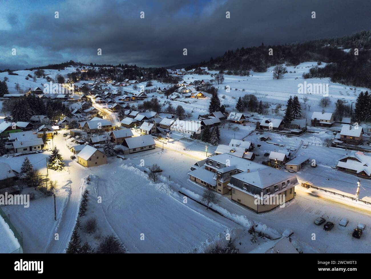 View of snowy mountain range and village with illuminated houses ...