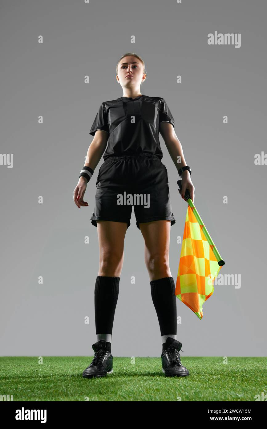 Young woman, female referee in uniform standing with flag, controlling ...