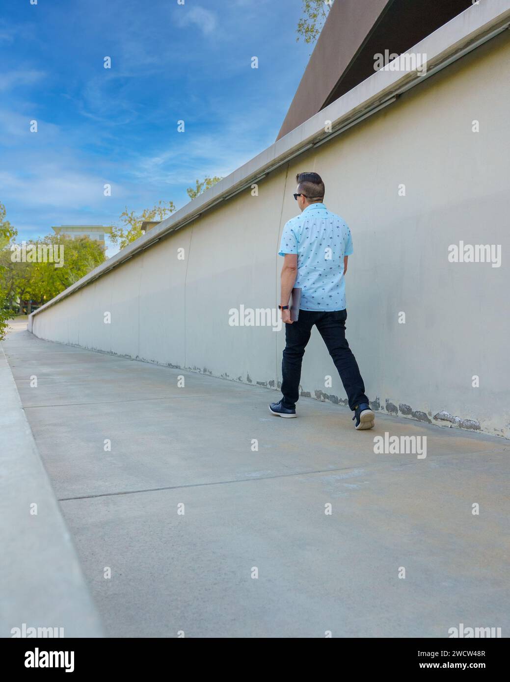 Man walking to work with a laptop under his arm Stock Photo - Alamy