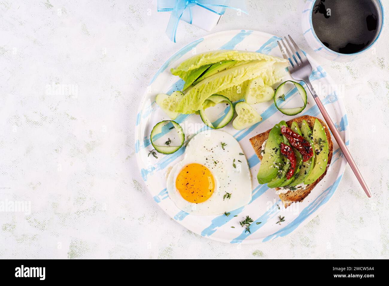 Romantic breakfast for Valentine's Day. Fried egg and toast with avocado and cream cheese. Top ...
