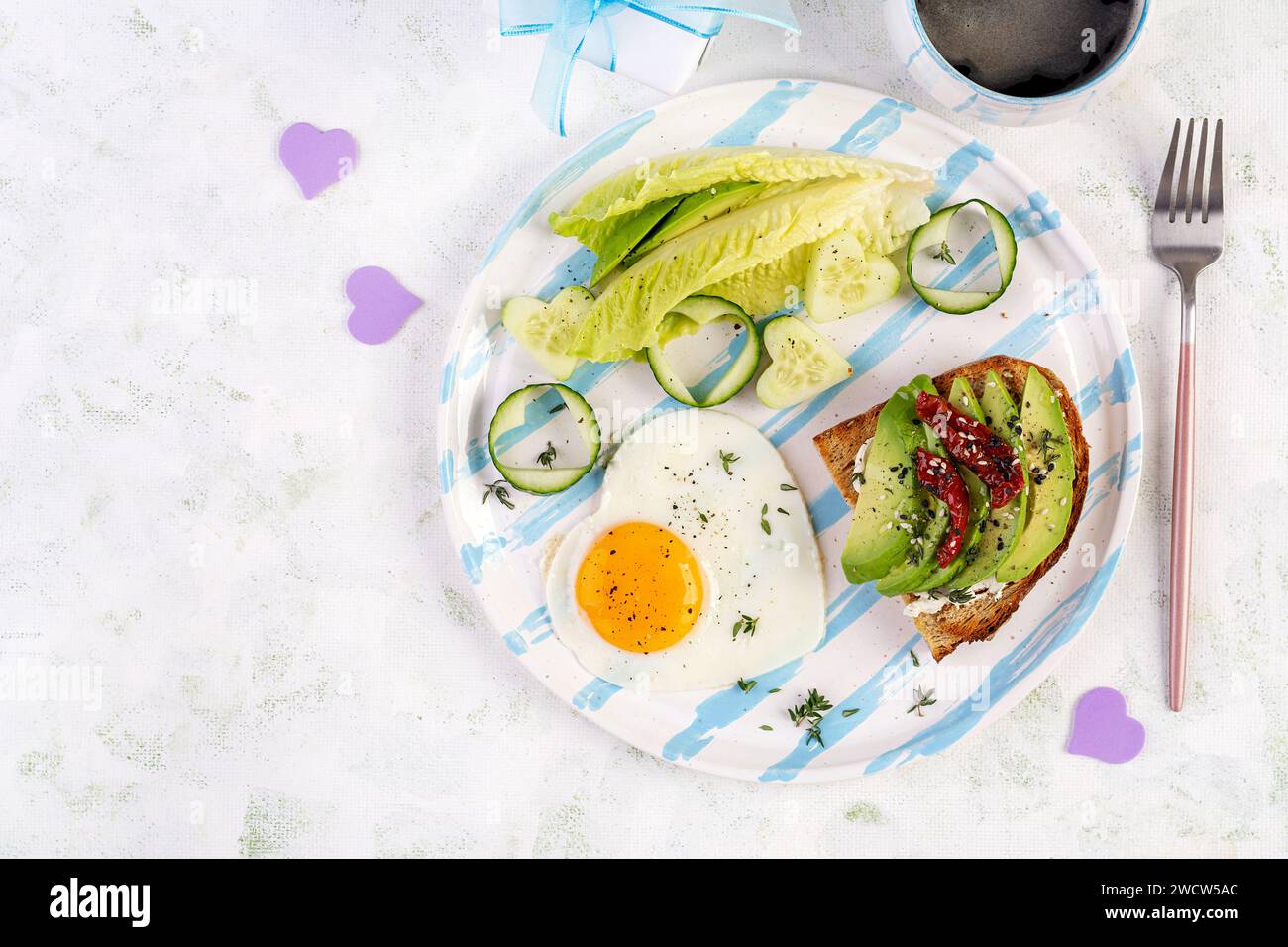 Romantic breakfast for Valentine's Day. Fried egg and toast with avocado and cream cheese. Top ...