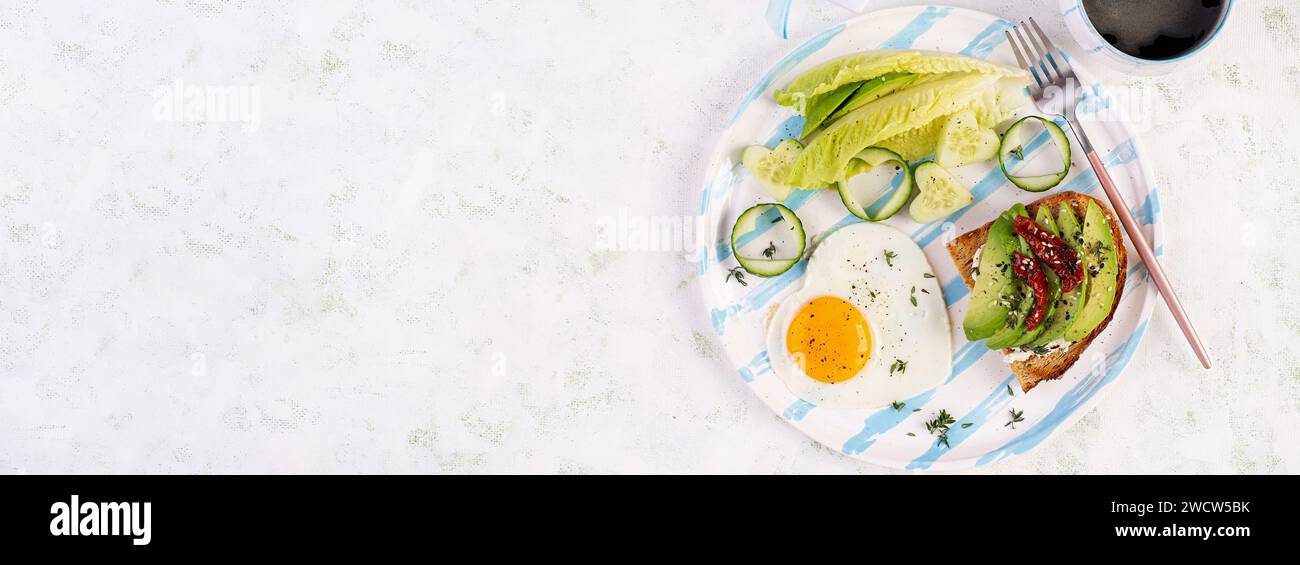 Romantic breakfast for Valentine's Day. Fried egg and toast with avocado and cream cheese. Top ...