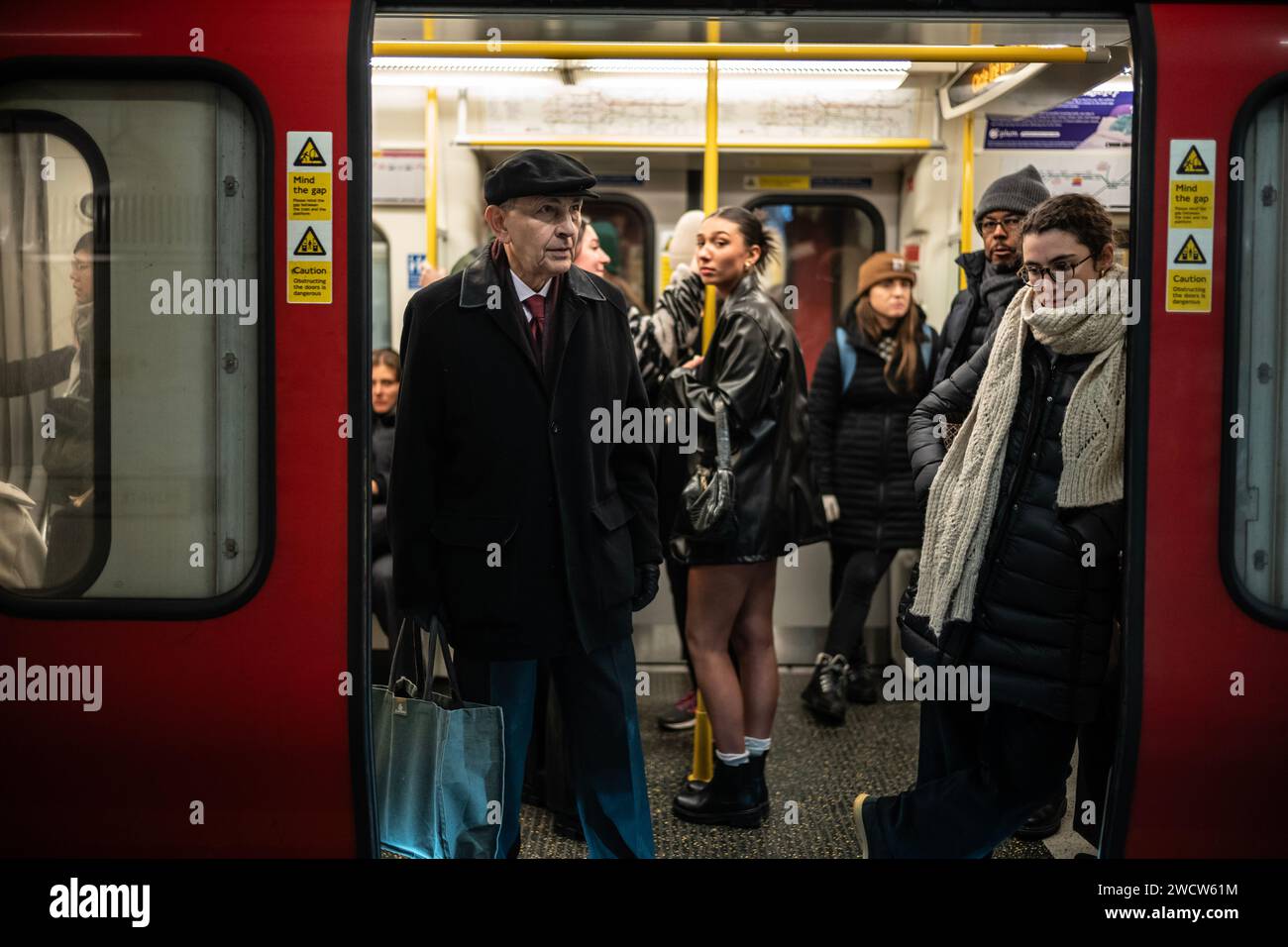 Commuters from various generations stand inside a London Underground ...