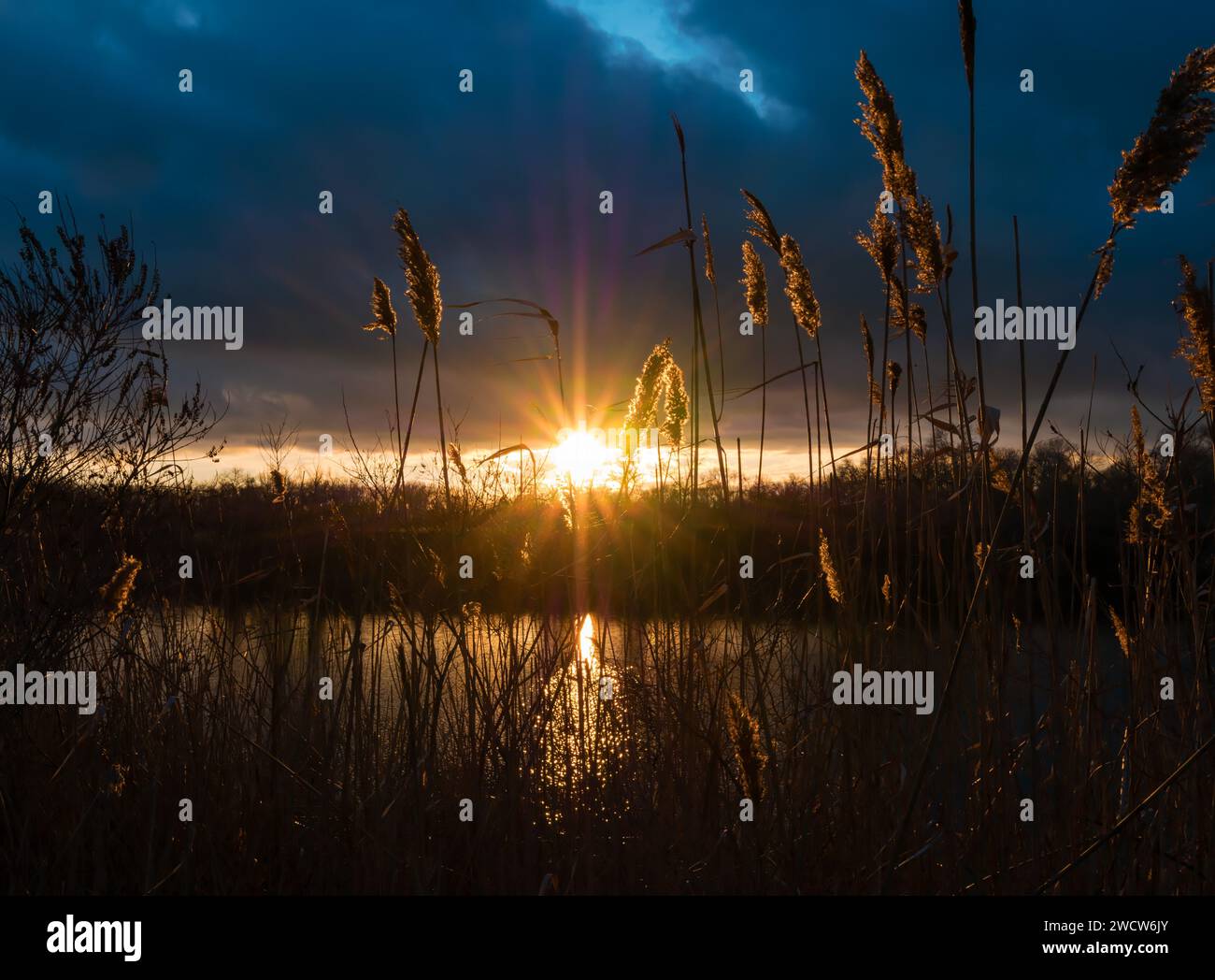 The rays of the sun at sunset breaking through thick dark clouds and ...