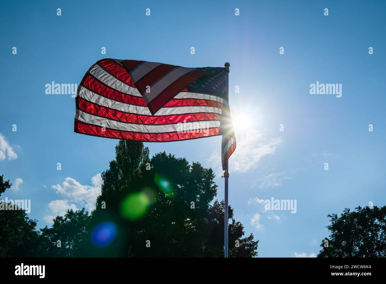The US flag flutters in the wind in the backlight of the sun's rays ...