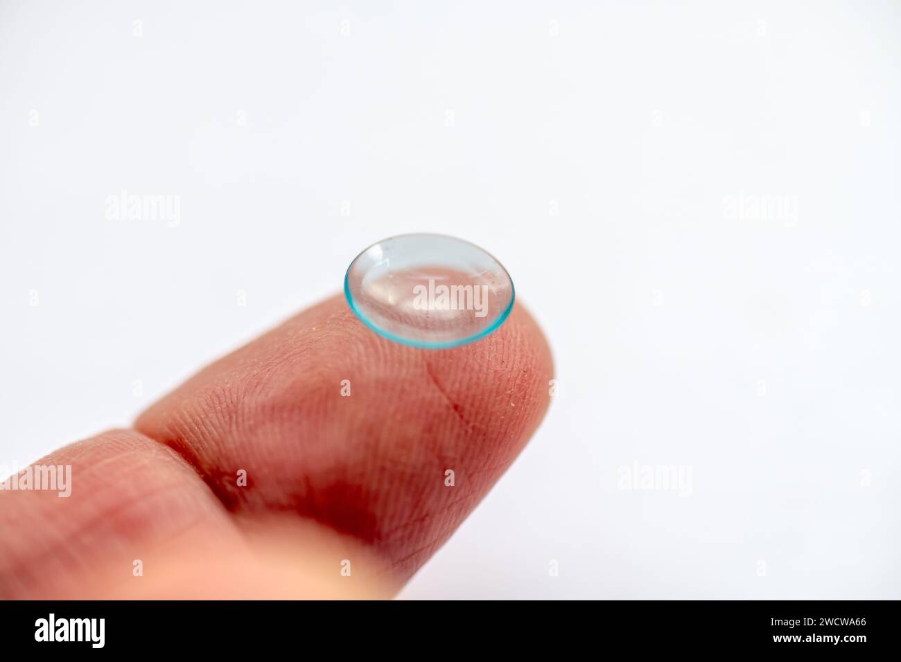 A finger with a eye contact lens on top isolated in a white background ...
