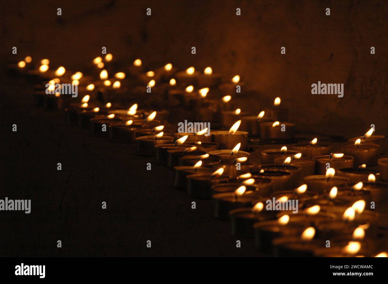 Glowing flames of wax, memorial tea candles burning on a stone ledge in ...