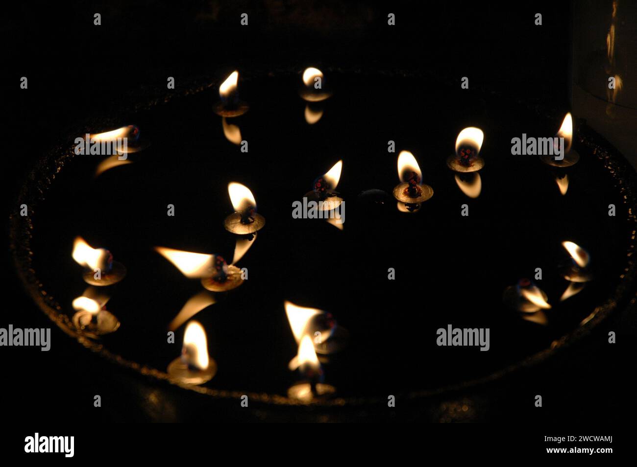 Glowing light cast by buring wicks floating in a plate of oil at a ...