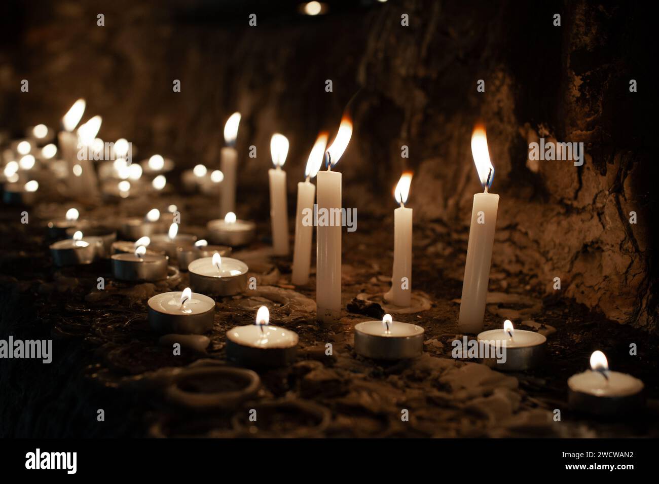 Glowing flames of wax, taper and tea candles burning outside the tomb ...