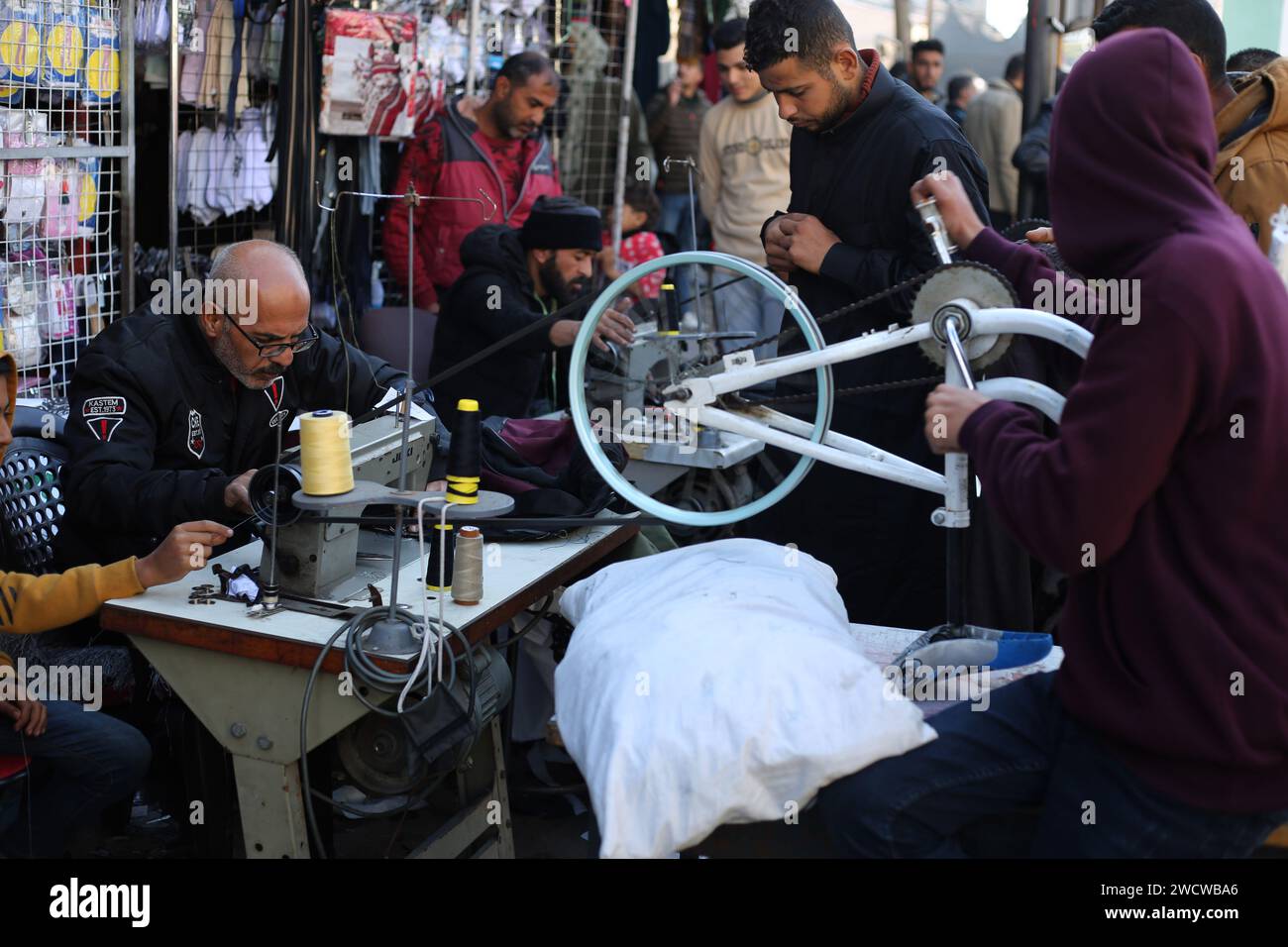 Gaza. 15th Jan, 2024. People operate a sewing machine driven by a ...