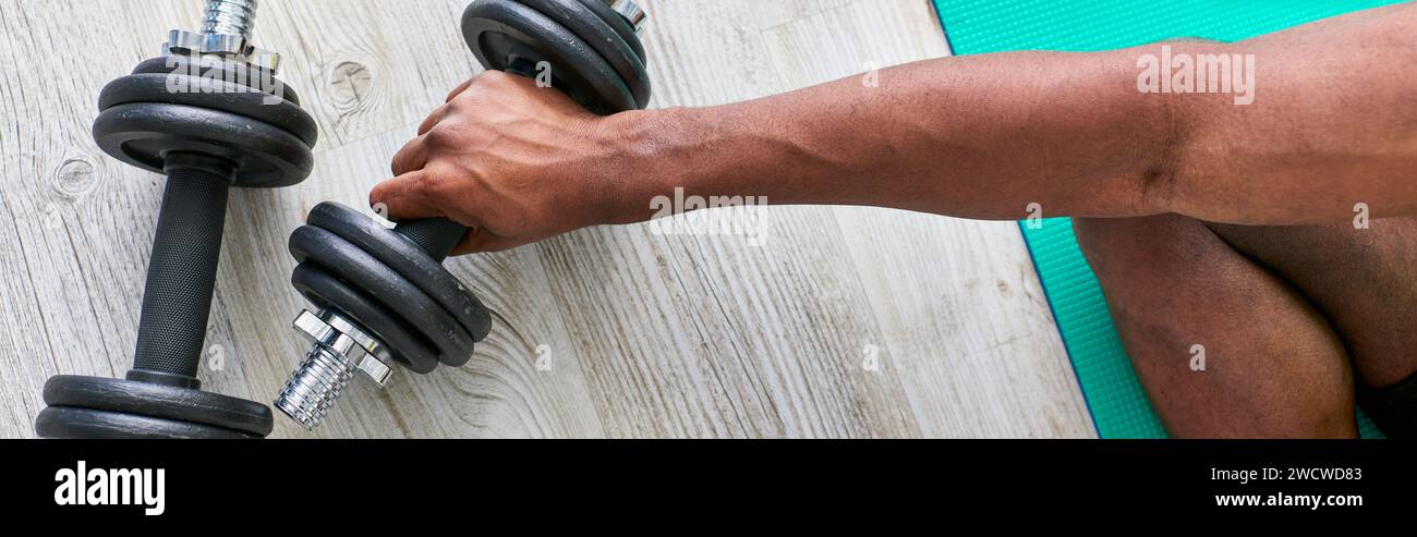 partial view of sporty african american man sitting on fitness mat and ...