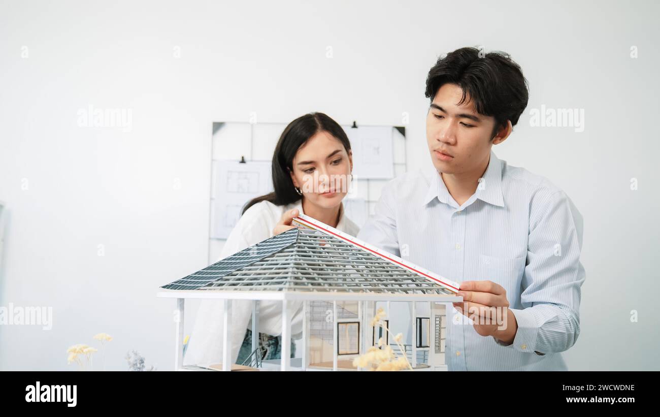 Professional young beautiful architect engineer using ruler and pencil measuring model roof ...