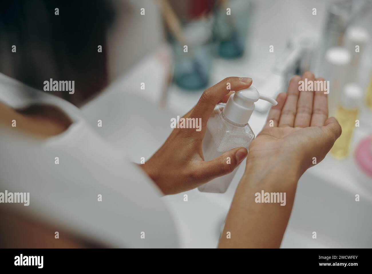 Close up of woman pouring body lotion on hand after having shower in ...