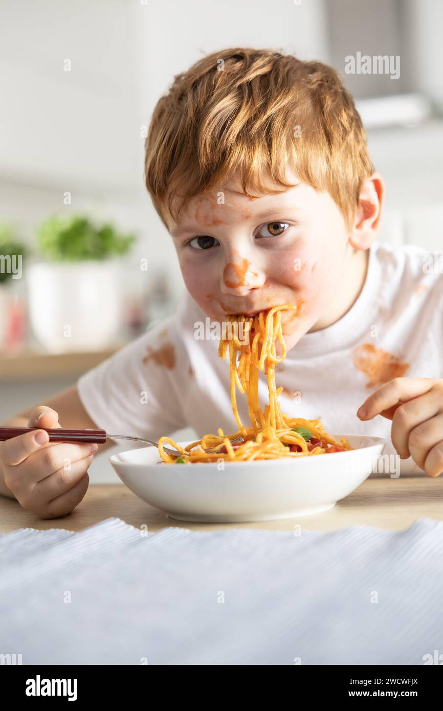 A cute little boy is eating spaghetti bolognese for lunch in the ...