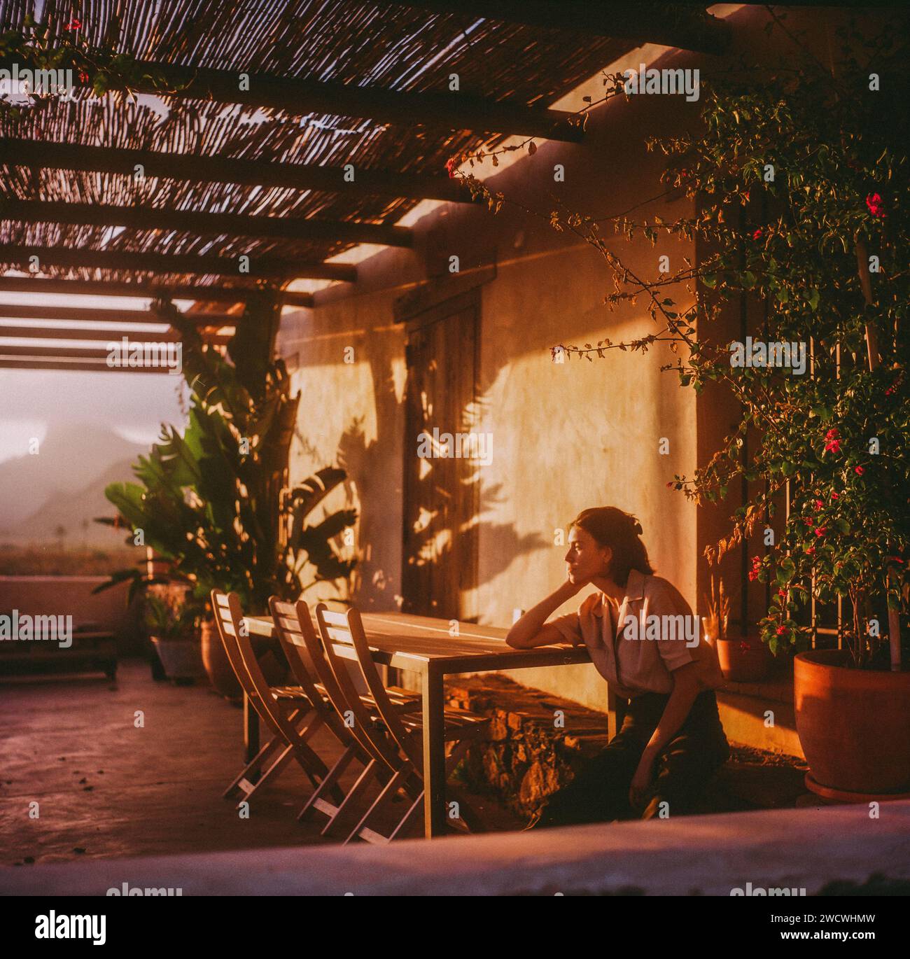 A young woman sitting on a terrace during a golden hour with an amazing ...