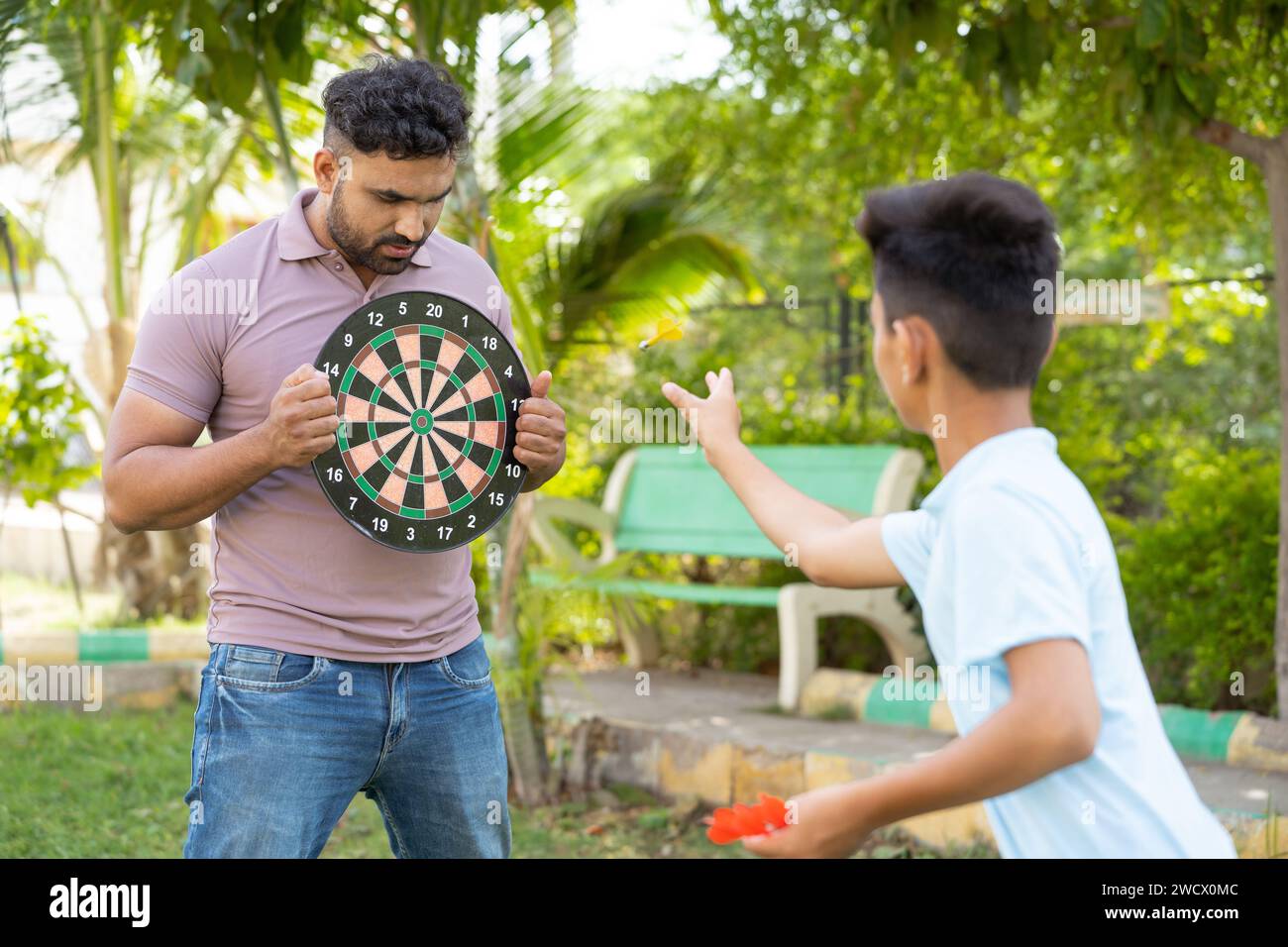 indian son throwing magnetic dart on dartboard while cheerful father ...
