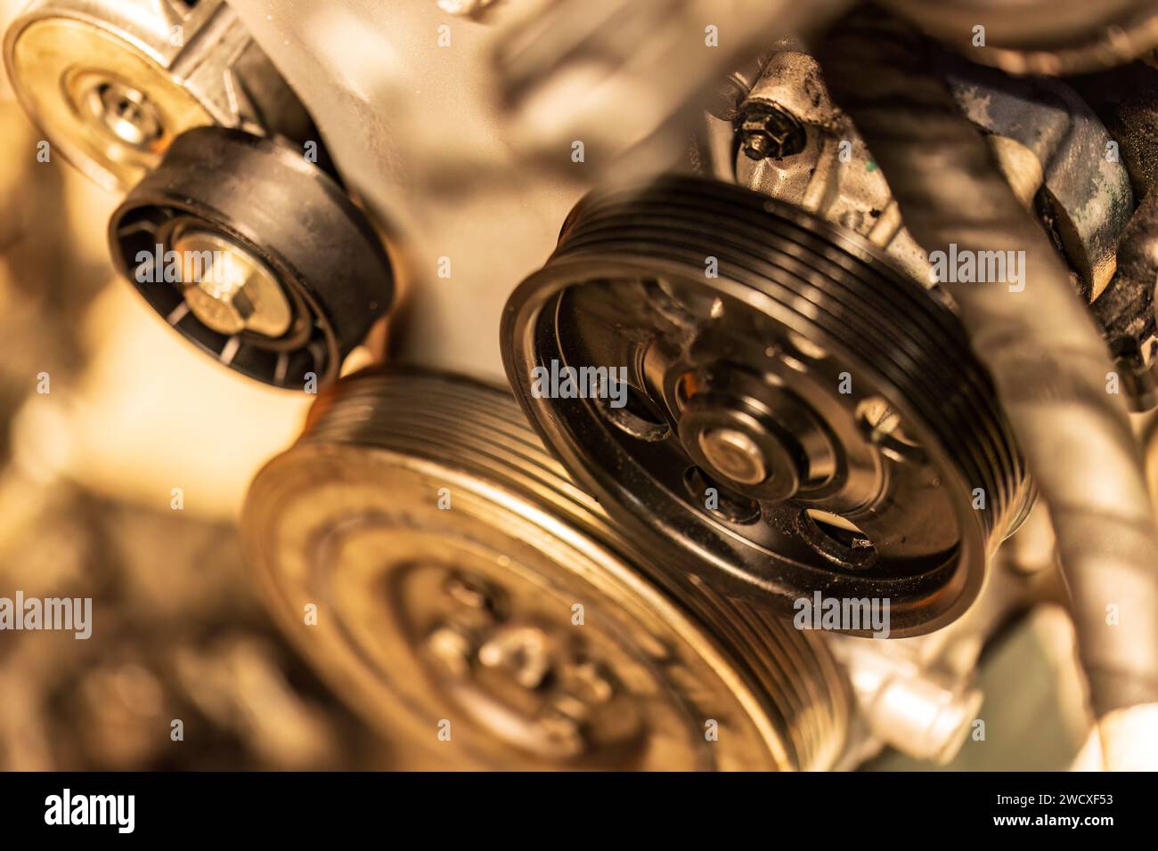 Photo focusing on the intricate pulleys of a car engine, highlighting ...
