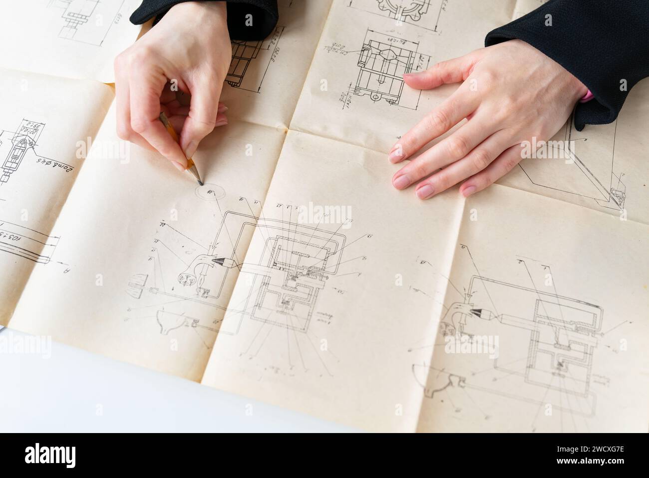This image shows hands reviewing architectural blueprints for ...