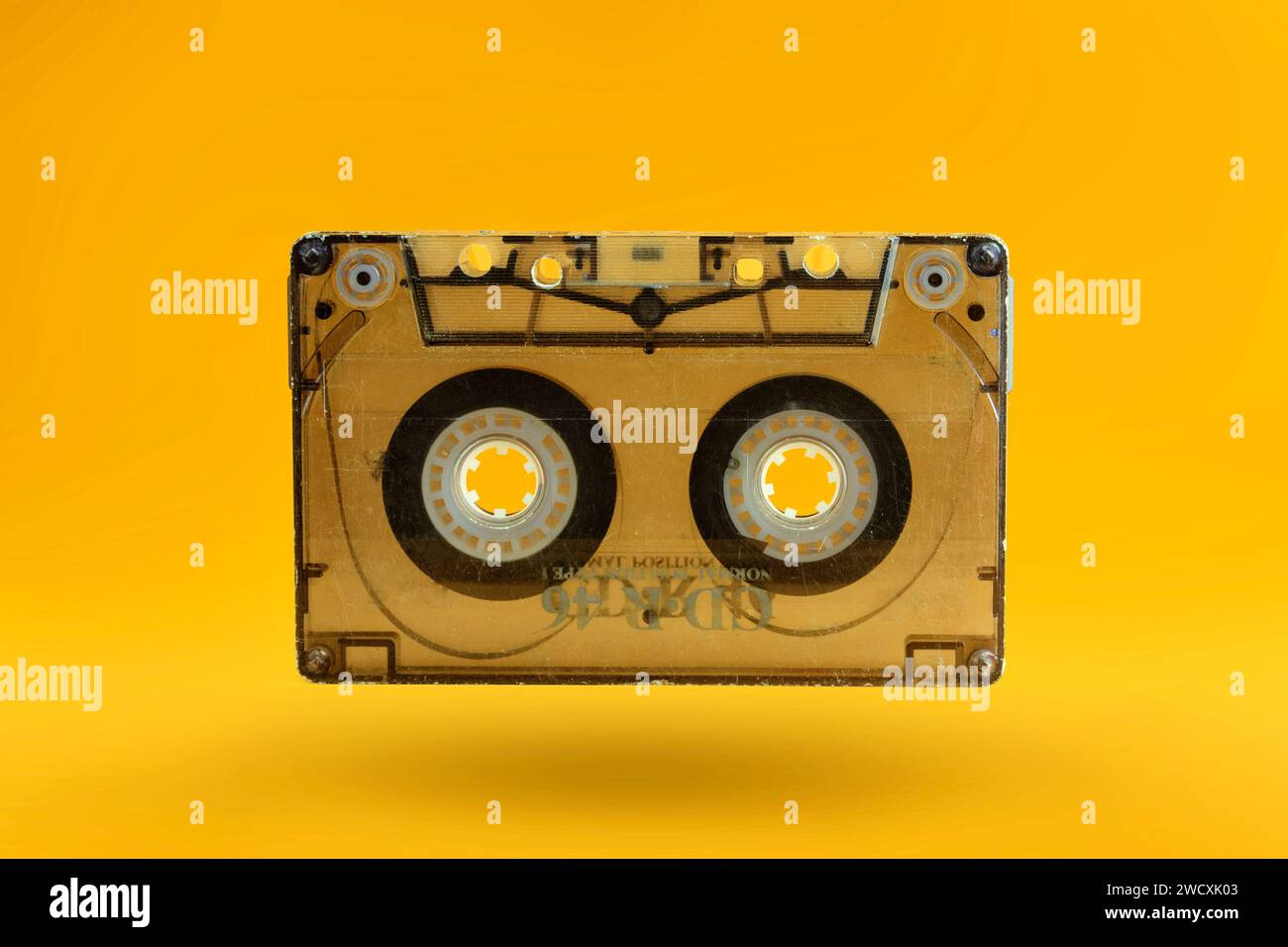 Old tape cassette with dust and scratches on yellow background. Retro ...