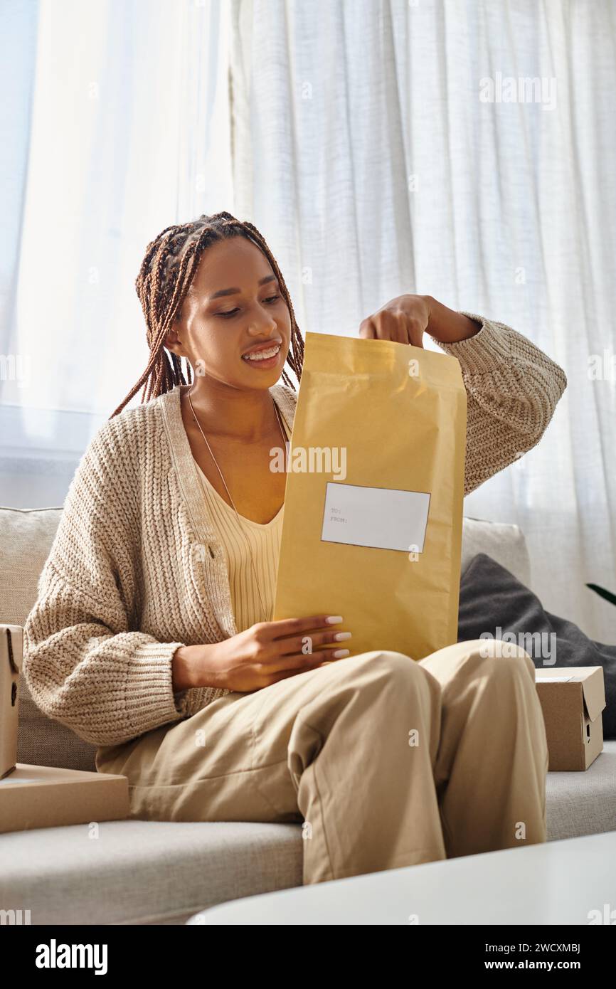 cheerful young african american woman with braces sitting on couch and ...