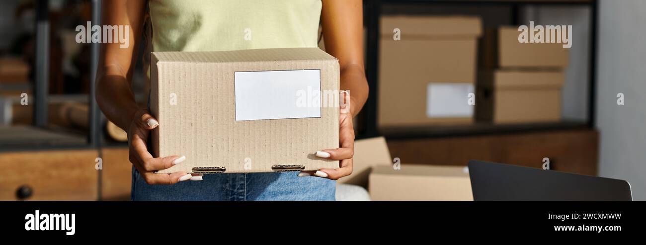 cropped view of happy african american woman with box in hands while ...