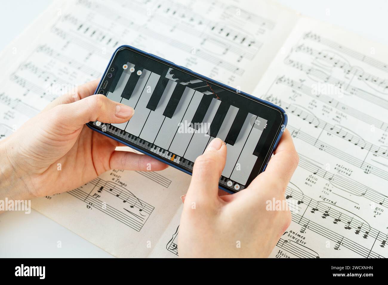This image shows a person s hands holding a smartphone displaying piano ...