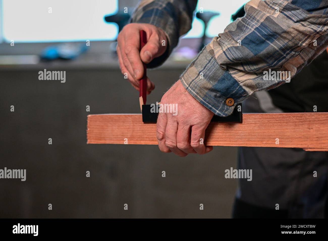 a worker marks a straight line with a right-angled triangle and a wood ...