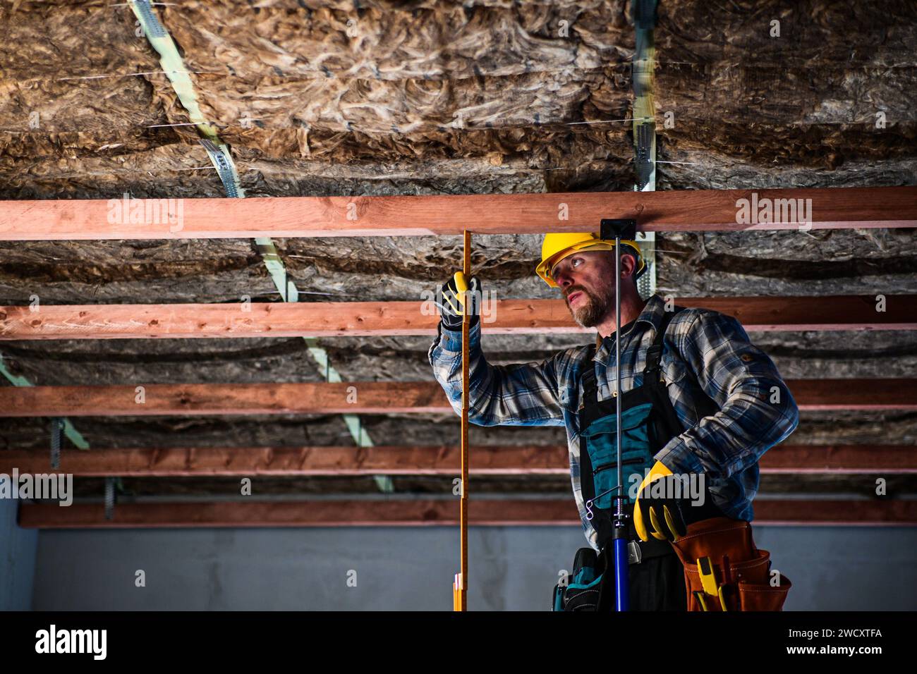 a worker in overalls and a protective helmet with yellow gloves ...