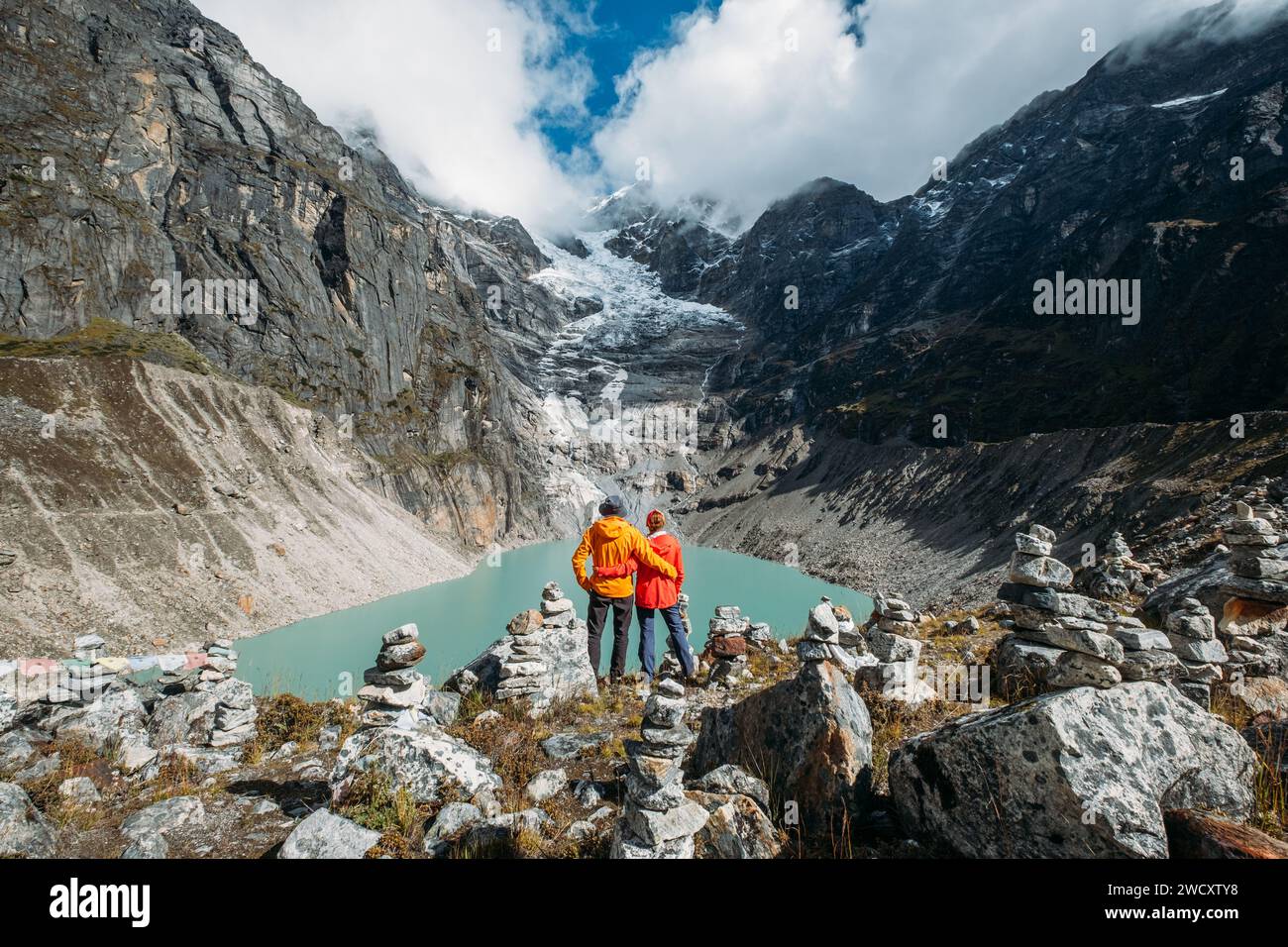 Trekkers couple dressed bright waterproof jackets hug on rock enjoying ...