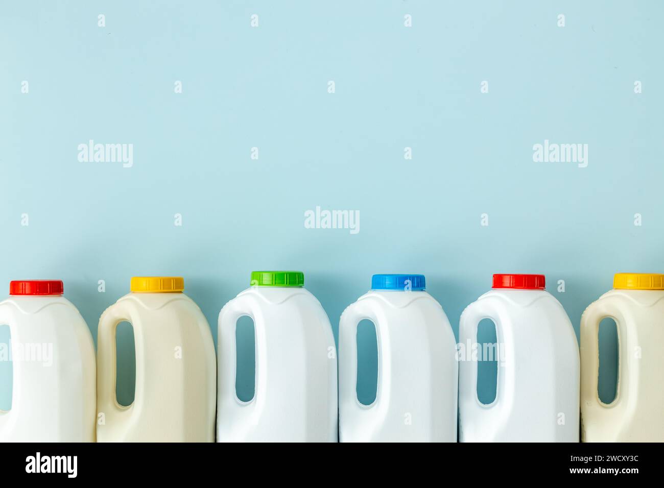White plastic bottles with colorful caps on a beautiful blue pastel ...