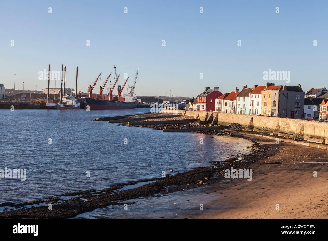 The beach,sea walls and Georgian houses with the cranes in the ...
