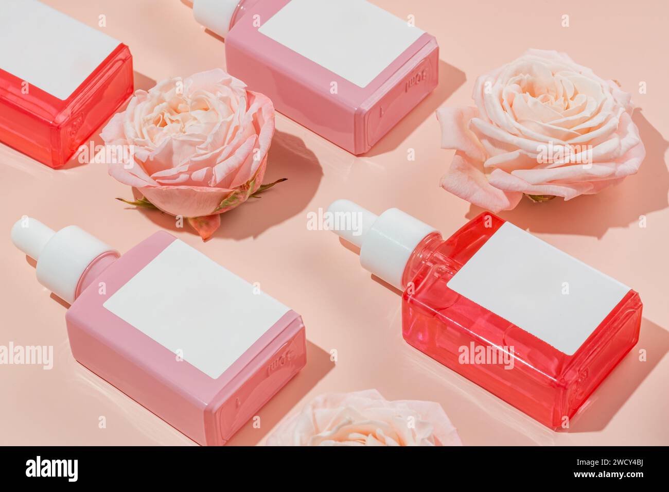 anti-aging rose collagen facial serum in square glass bottles on pink ...