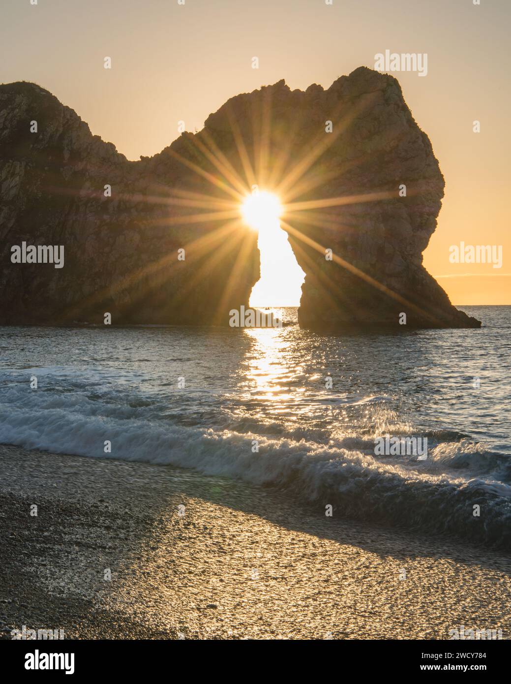 Durdle Door during winter Solstice as the sun rises through the arch ...