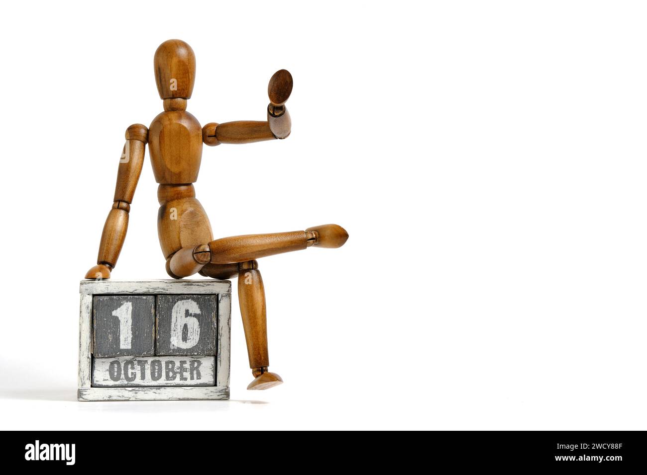 October 16, wooden calendar with mannequin sitting on it on white ...